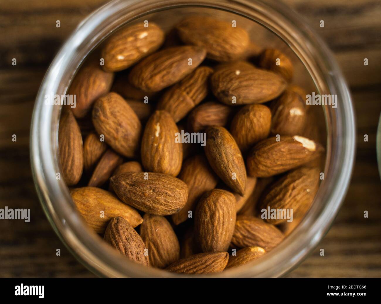 Almonds in a small plate on a vintage wooden table as a background with ...