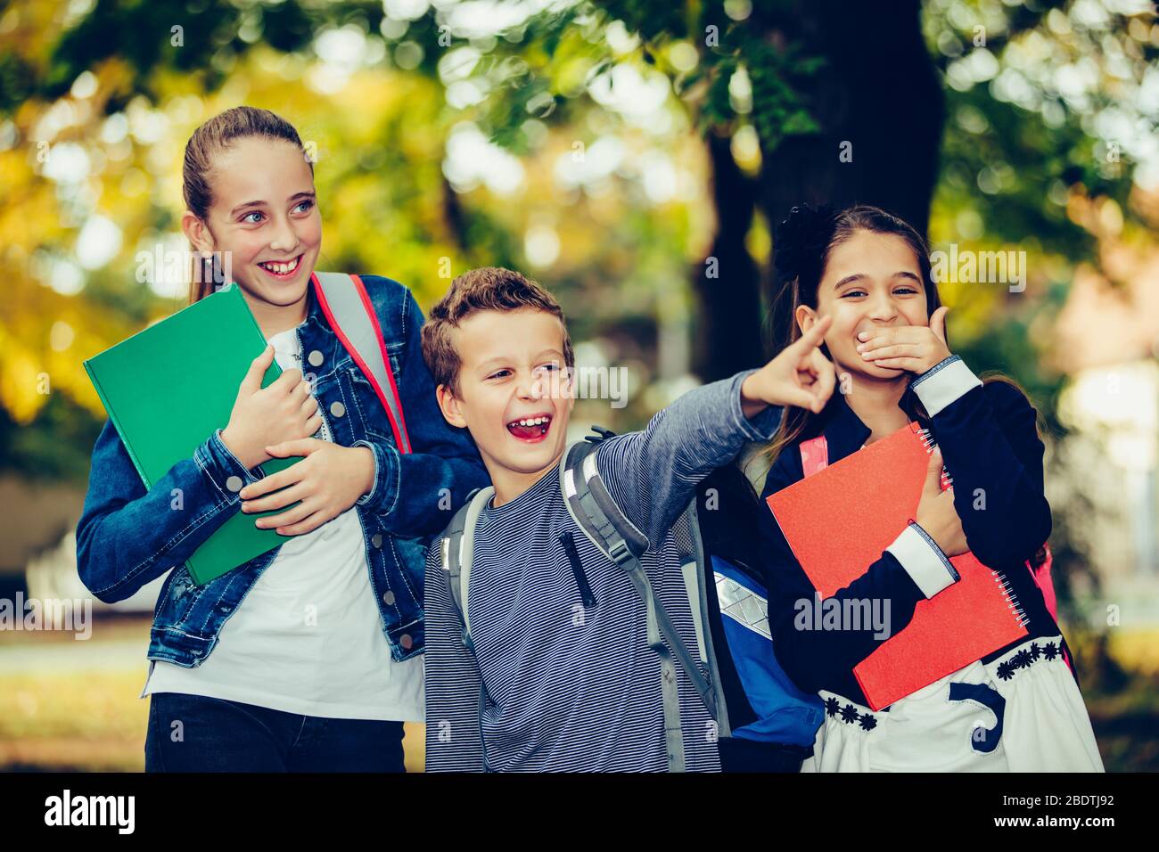 Back to school. Close up three happy friends with backpacks laughing ...