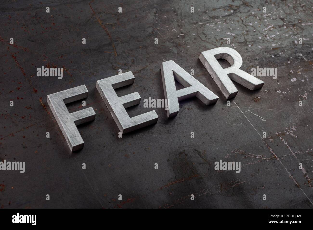 the word fear laid with silver letters on raw rusted steel sheet ...