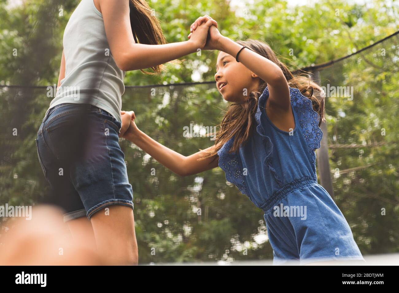 Little girls jumping and playing on a trampoline Stock Photo - Alamy