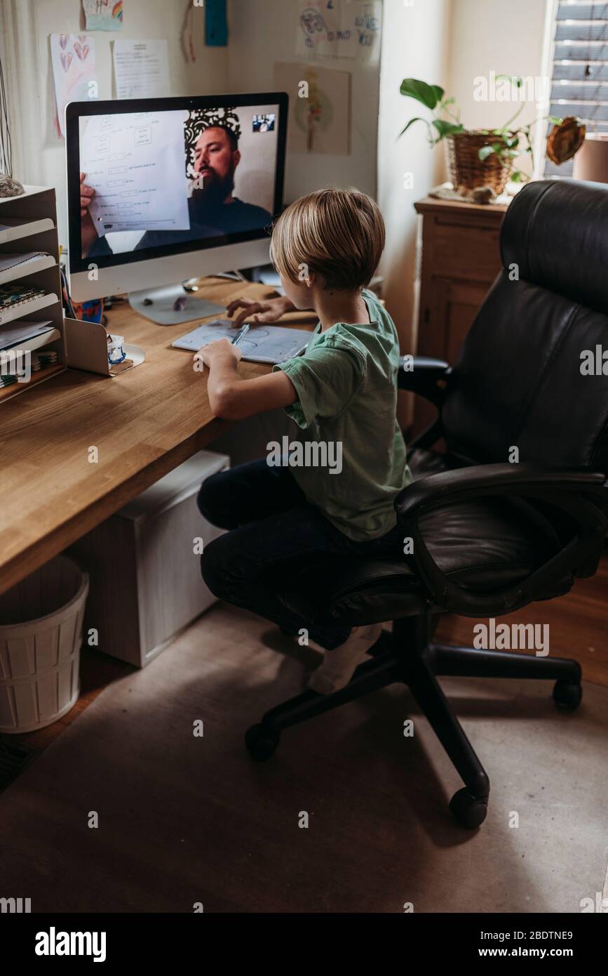 Elementary age boy taking online class from teacher during isolation ...