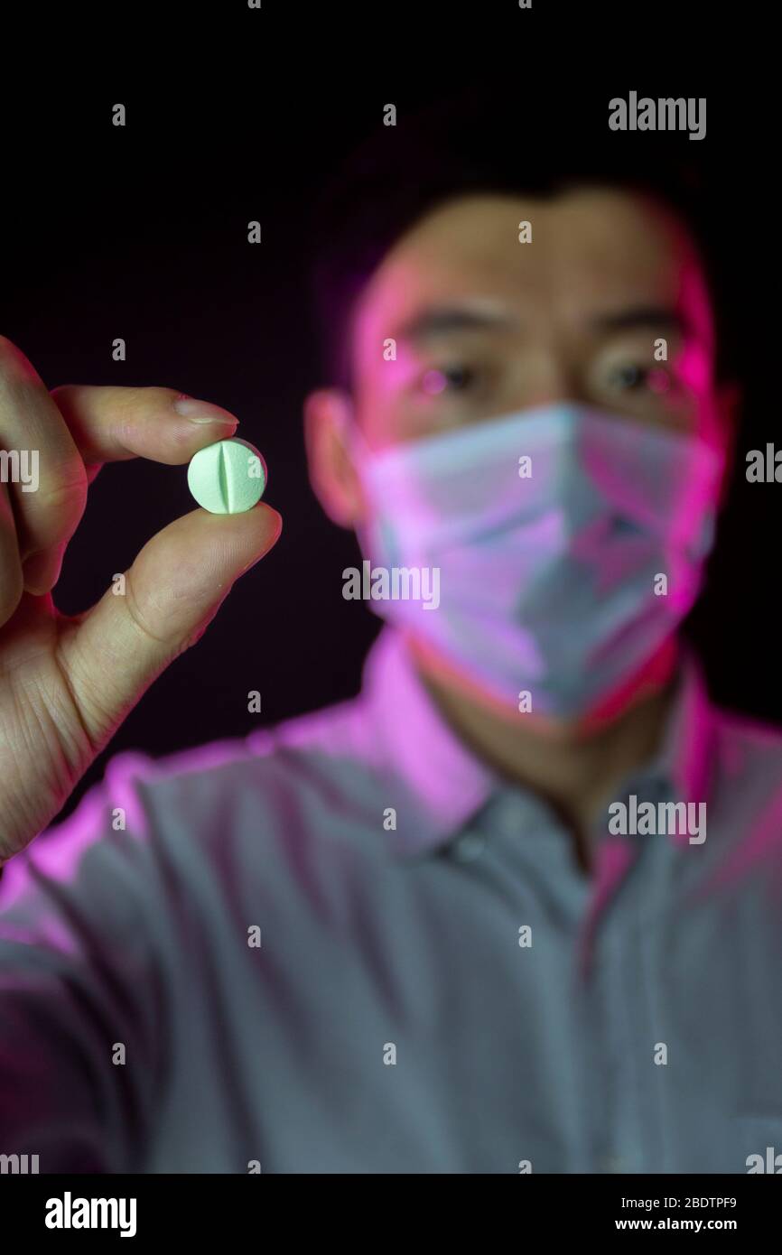 Pill in hand. Chinese man in protective mask against covid-19. Pandemic ...
