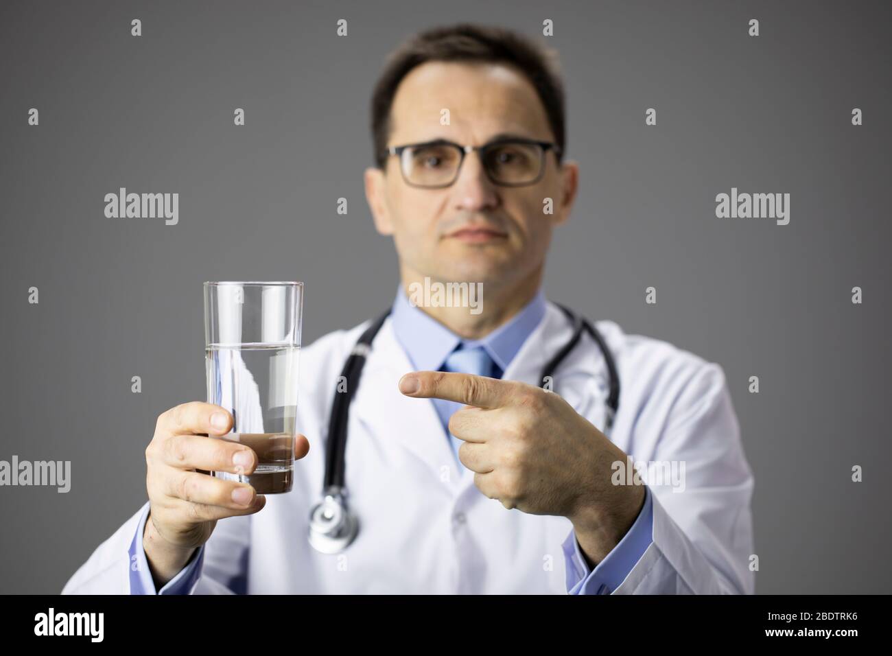 Doctor with stethoscope on neck holds a glass water in hands. Water ...