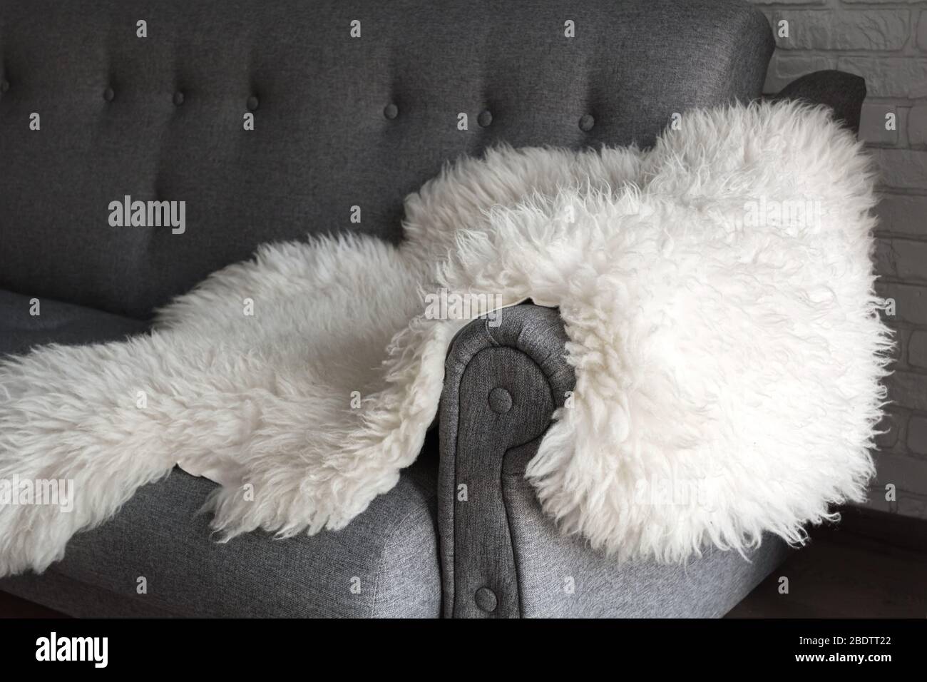 White sheep skin on a gray sofa. A cozy place to relax in the apartment ...