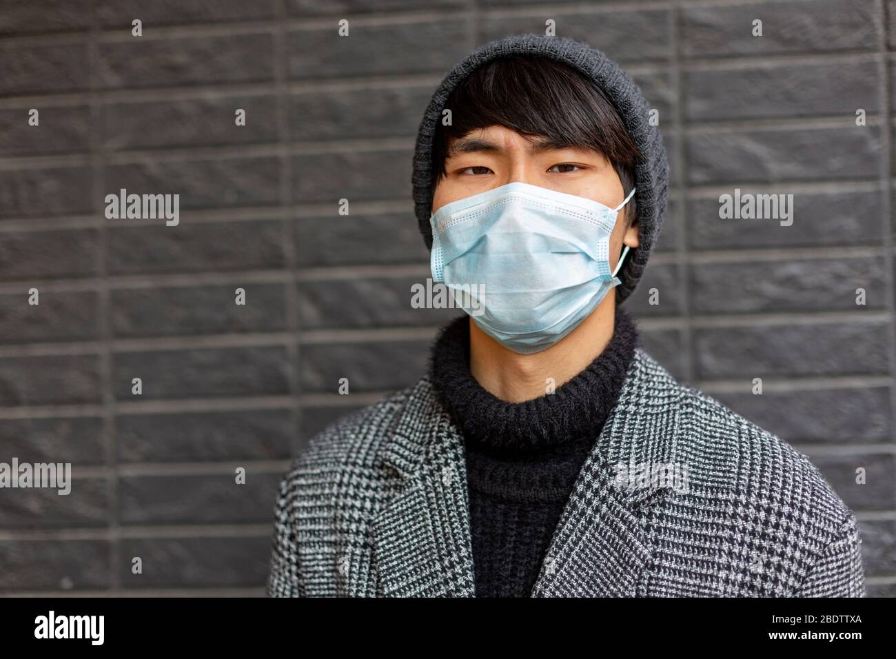 Young Chinese man in facial mask against 2019-nCov looks upset and ...