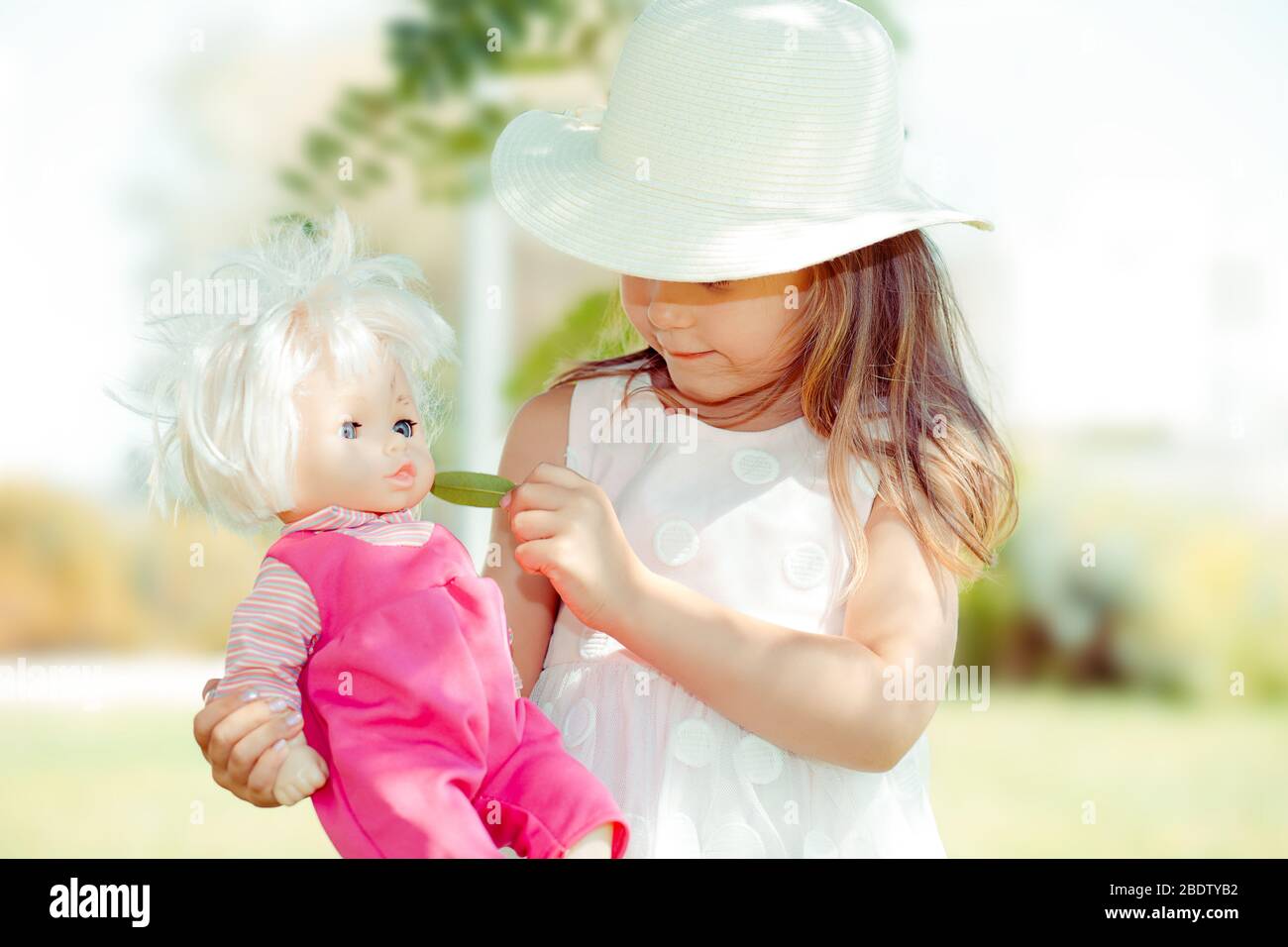 Girl feeding her doll. Closeup portrait head shot of playing giving to ...