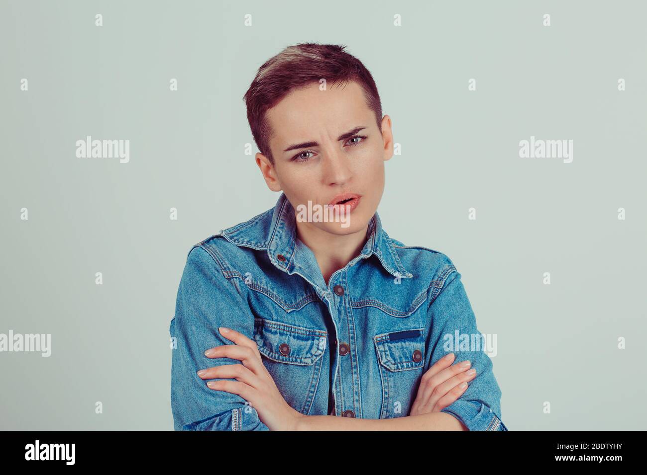 Skeptical grumpy woman looking at you camera, arms crossed blue jeans ...