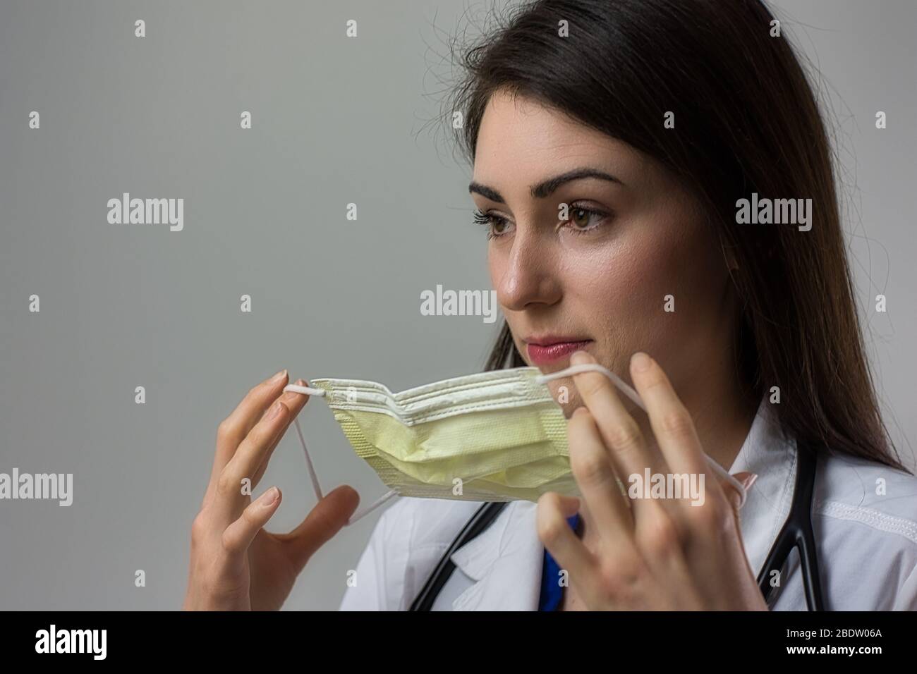 Female healthcare worker putting on mask. Donning PPE for safety in ...