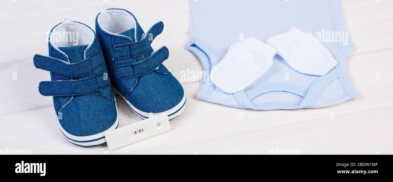 Pregnancy test with positive result and clothing for newborn, concept ...