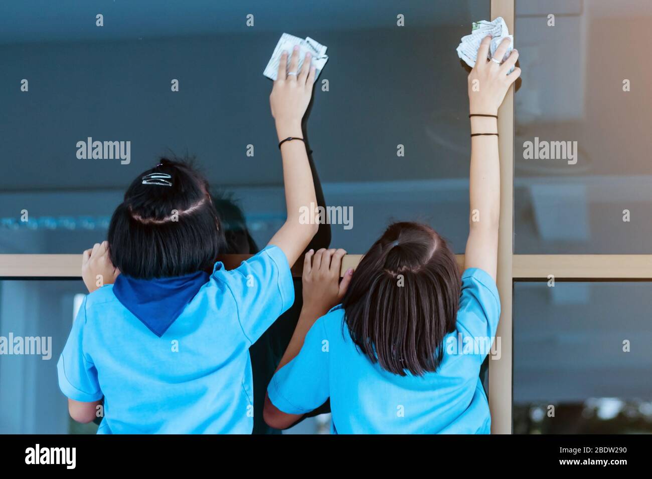 Back view of female students are helping to wipe the glass with wet ...