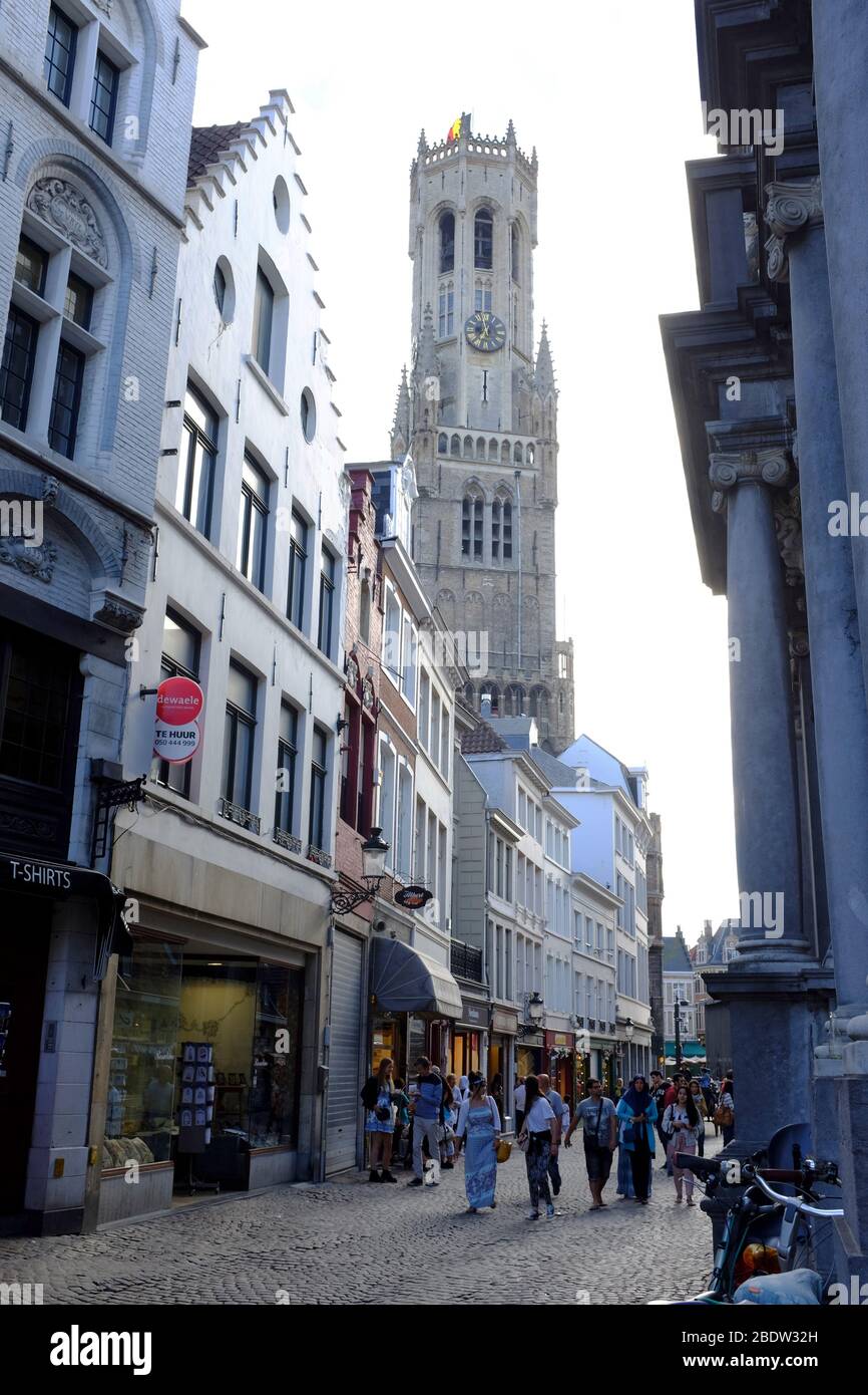 The view of Belfry of Bruges tower from a street in historic center of ...