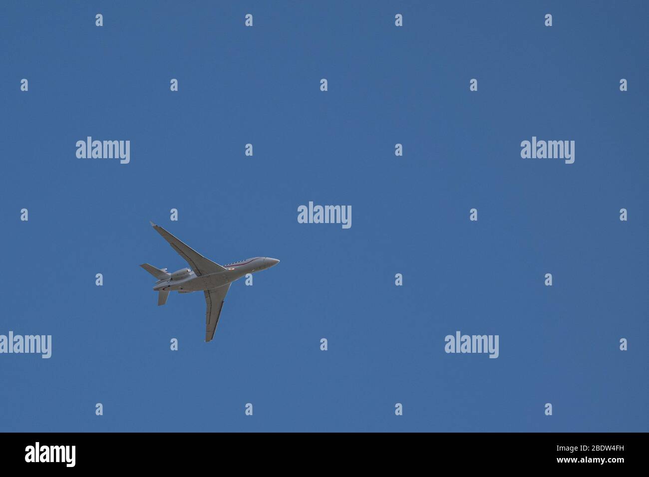 a small white jet airplane flies in the blue almost cloudless sky Stock ...