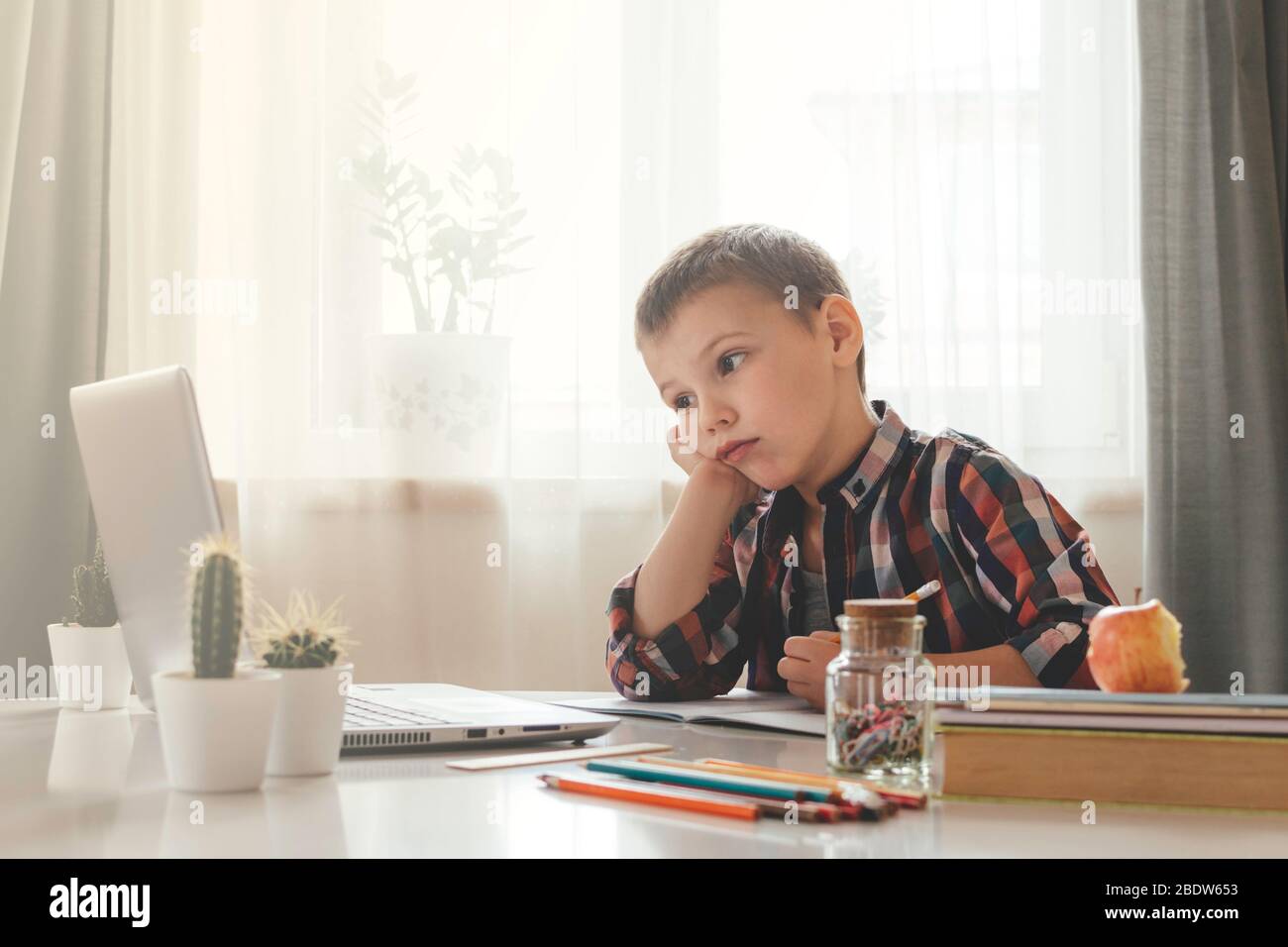 Boy studying at home with notebook and doing school homework. Distance learning online education ...