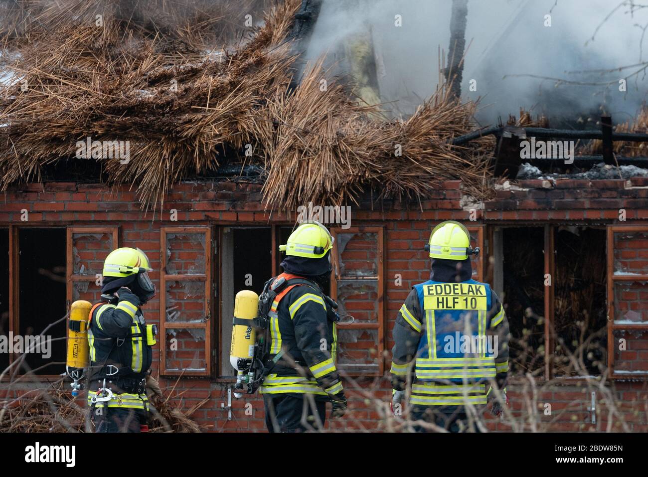 Eddelak, Germany. 10th Apr, 2020. Firefighters stand in front of a ...