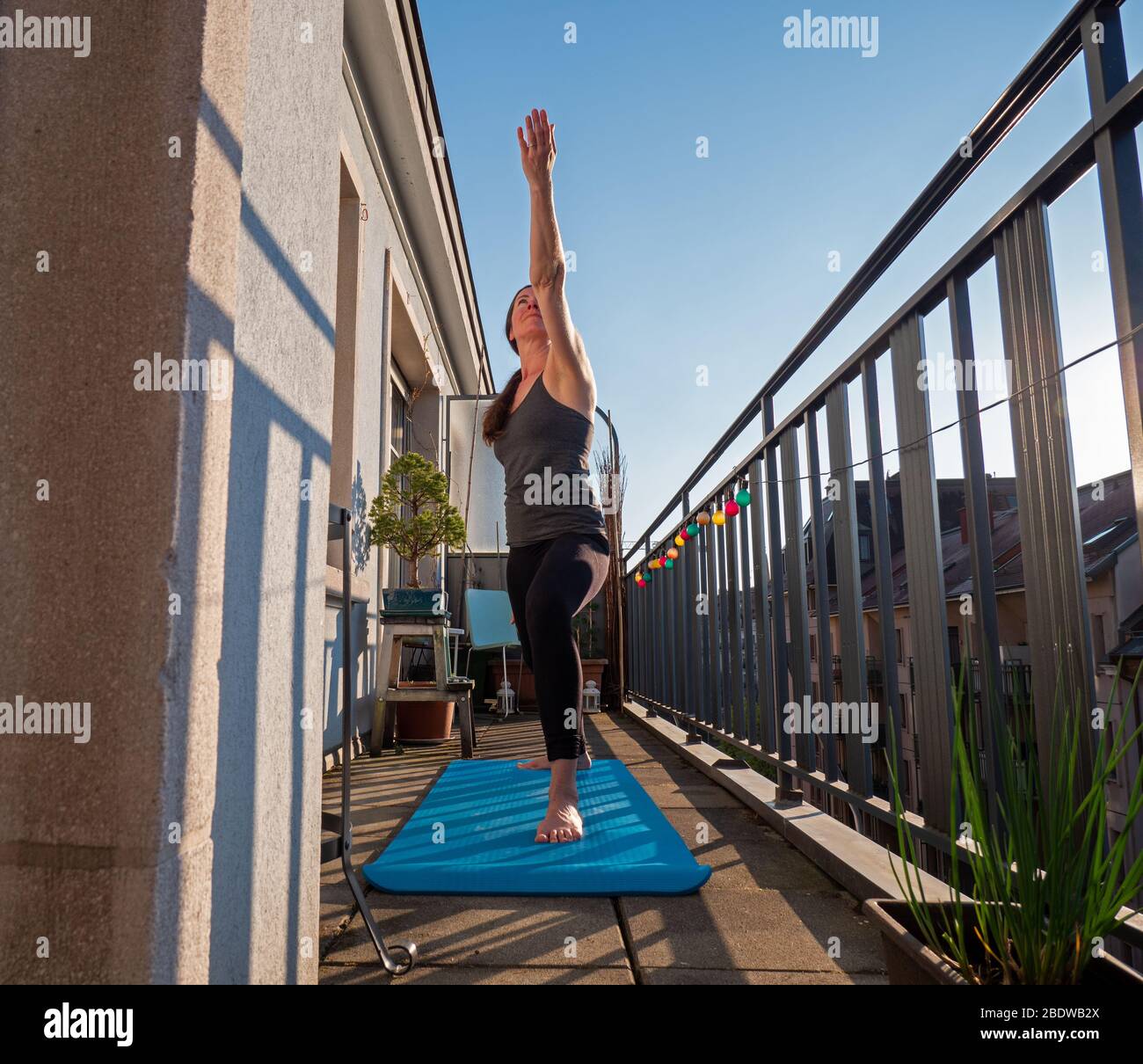 A woman practices yoga on the balcony of her apartment during the Covid ...