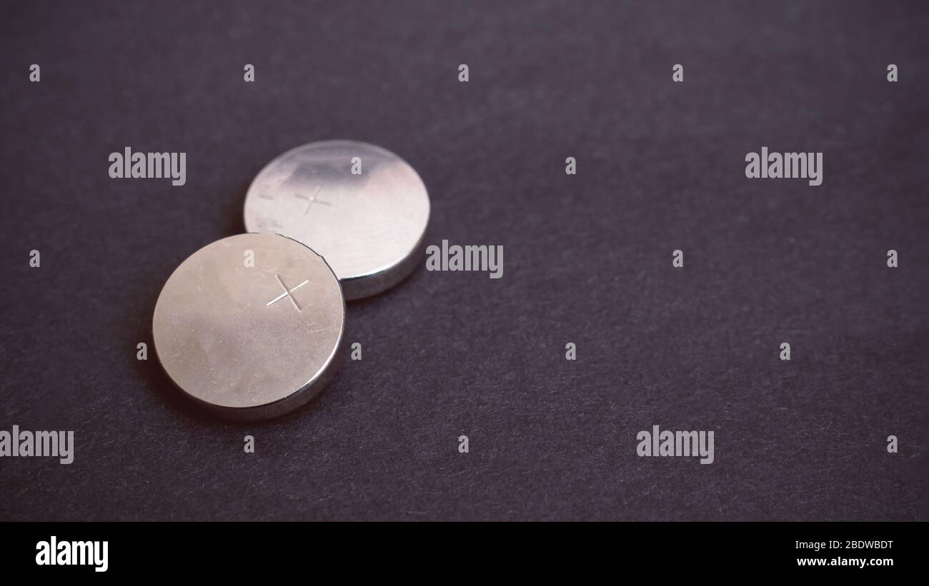 Two round batteries on a black background Stock Photo - Alamy