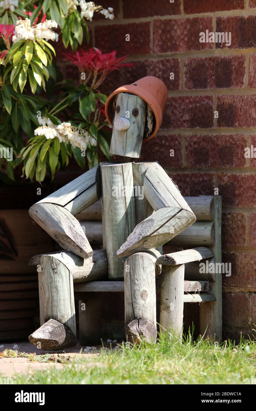 Garden Log Man sitting in a bench Stock Photo - Alamy