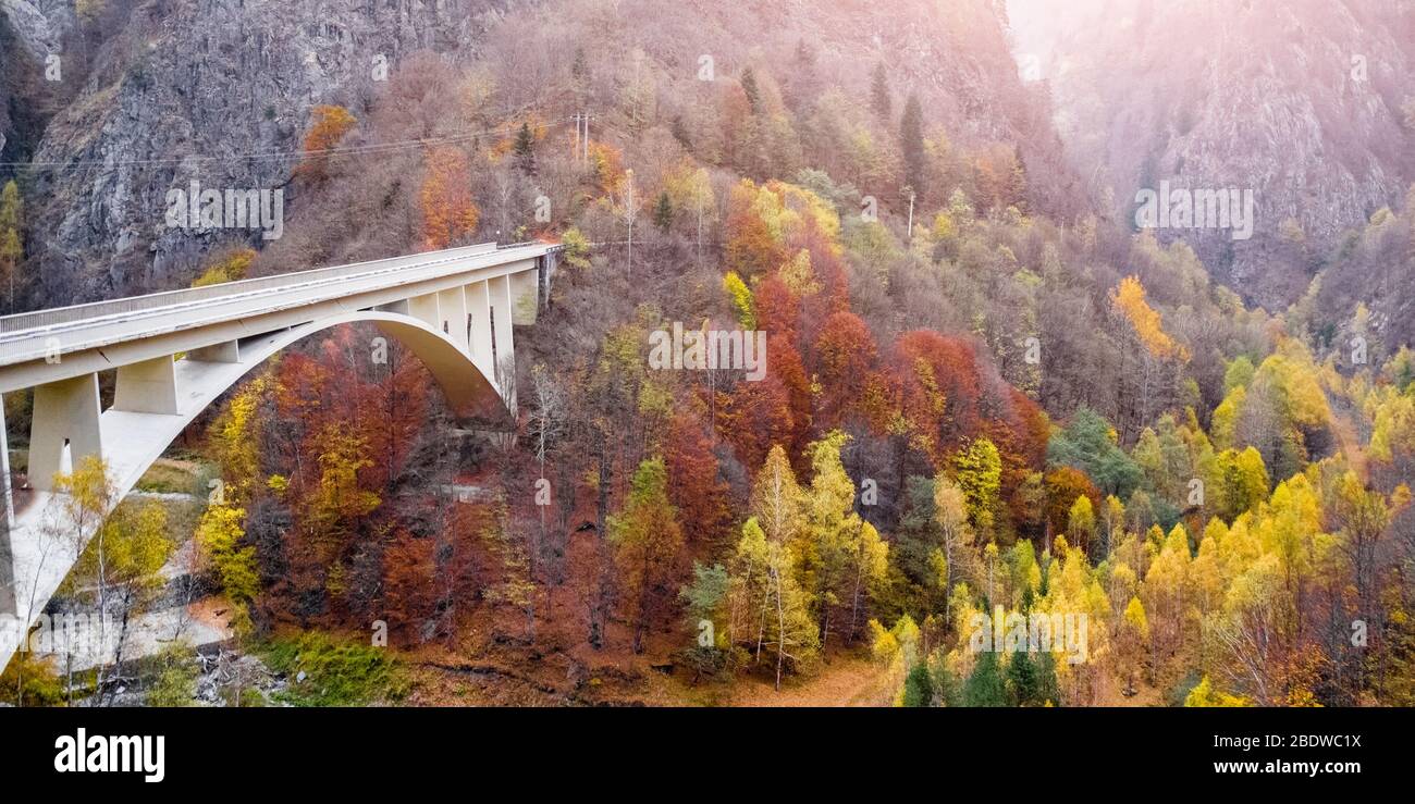 Bridge way between mountains covered with autumn trees Stock Photo - Alamy
