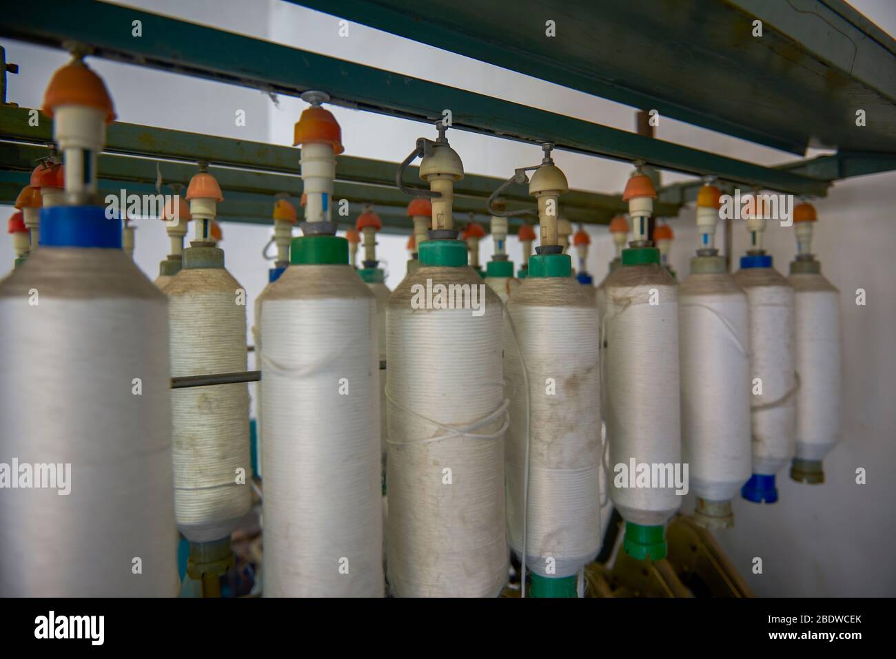 A row of bobbins on a cotton spinning machine Stock Photo - Alamy
