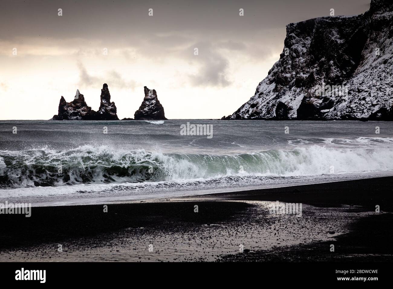 Reynisdrangar basalt sea stacks and Reynisfjall Cliffs covered with ...