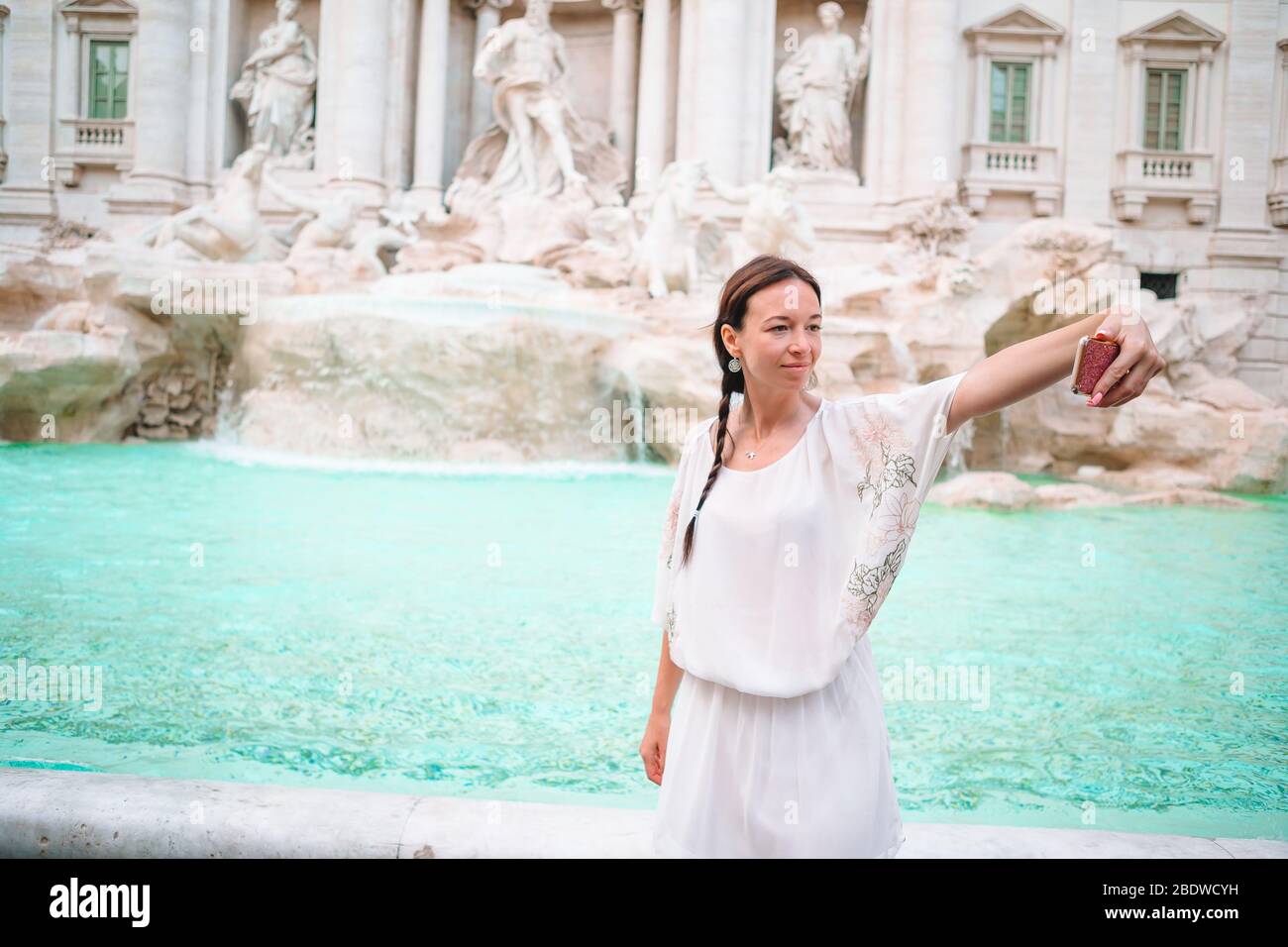 Pretty woman looking to the Fountain of Trevi during her trip in Rome ...