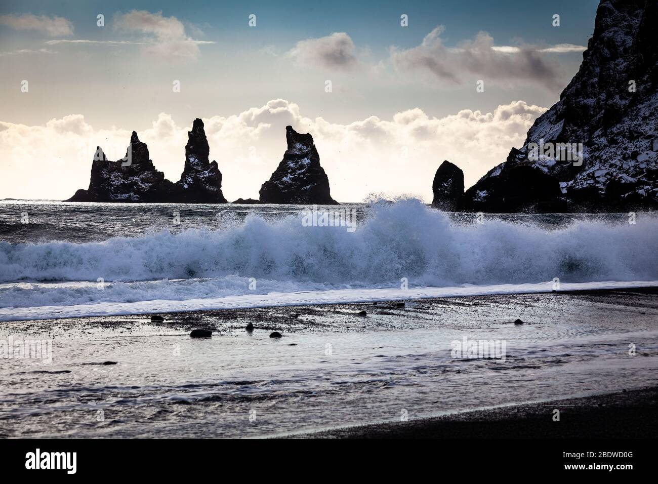 Reynisdrangar basalt sea stacks and Reynisfjall Cliffs covered with ...