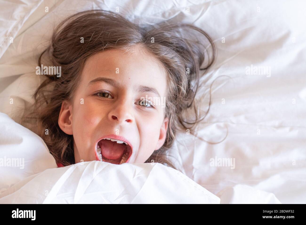 Portrait of a beautiful smiling girl waking up early in the morning ...