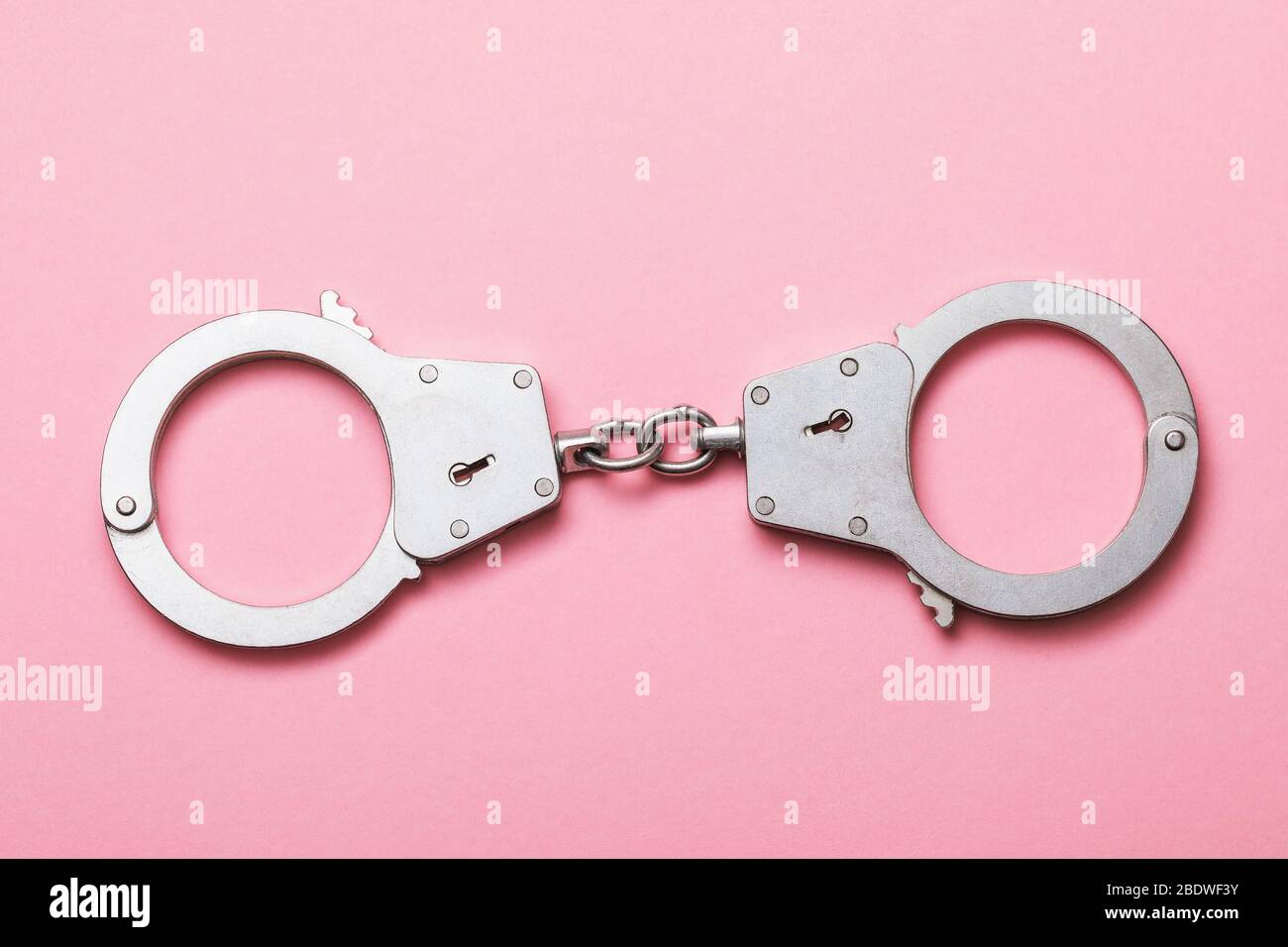 Closed handcuffs on a pink background. Top view on special equipment ...