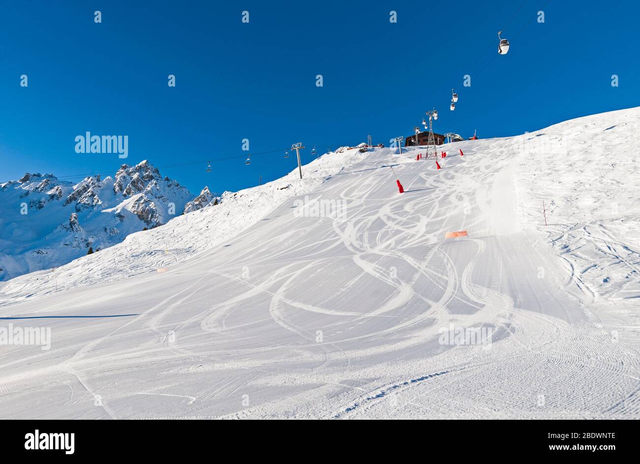 Panoramic landscape view up a large ski slope piste in winter alpine ...