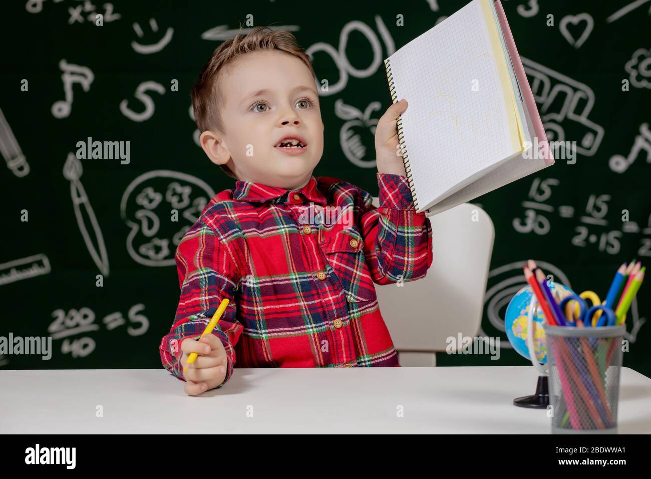 Cute child boy doing homework. Clever kid drawing at desk. Schoolboy ...