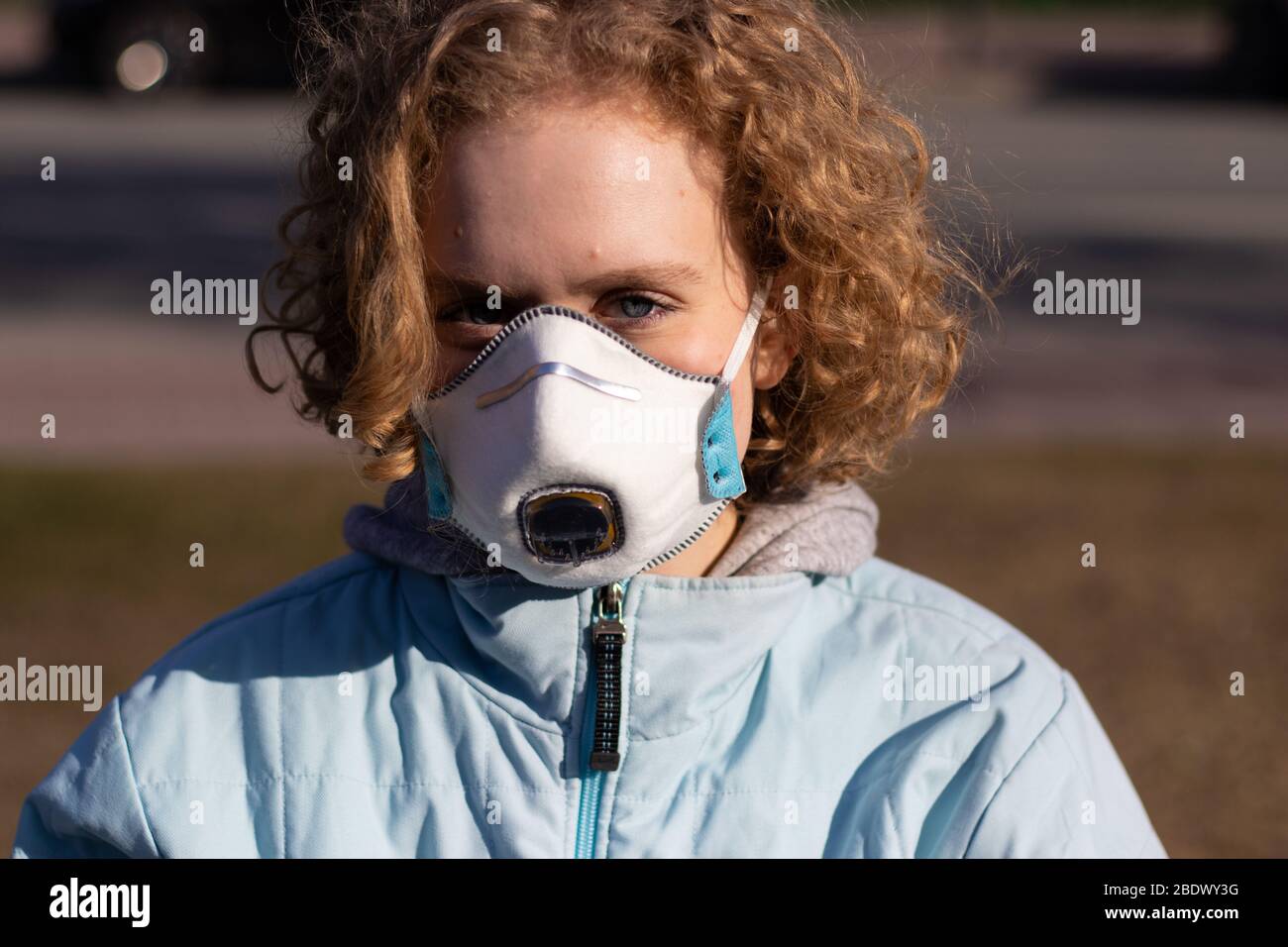 Beautiful girl with blonde curly hair in face protective mask look in ...
