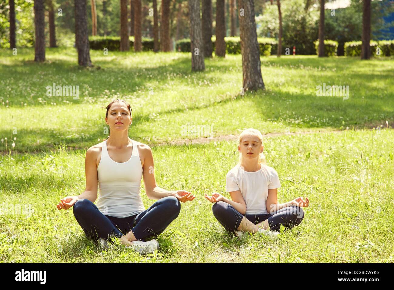 sporty mother and daughter. woman and child training in the park ...