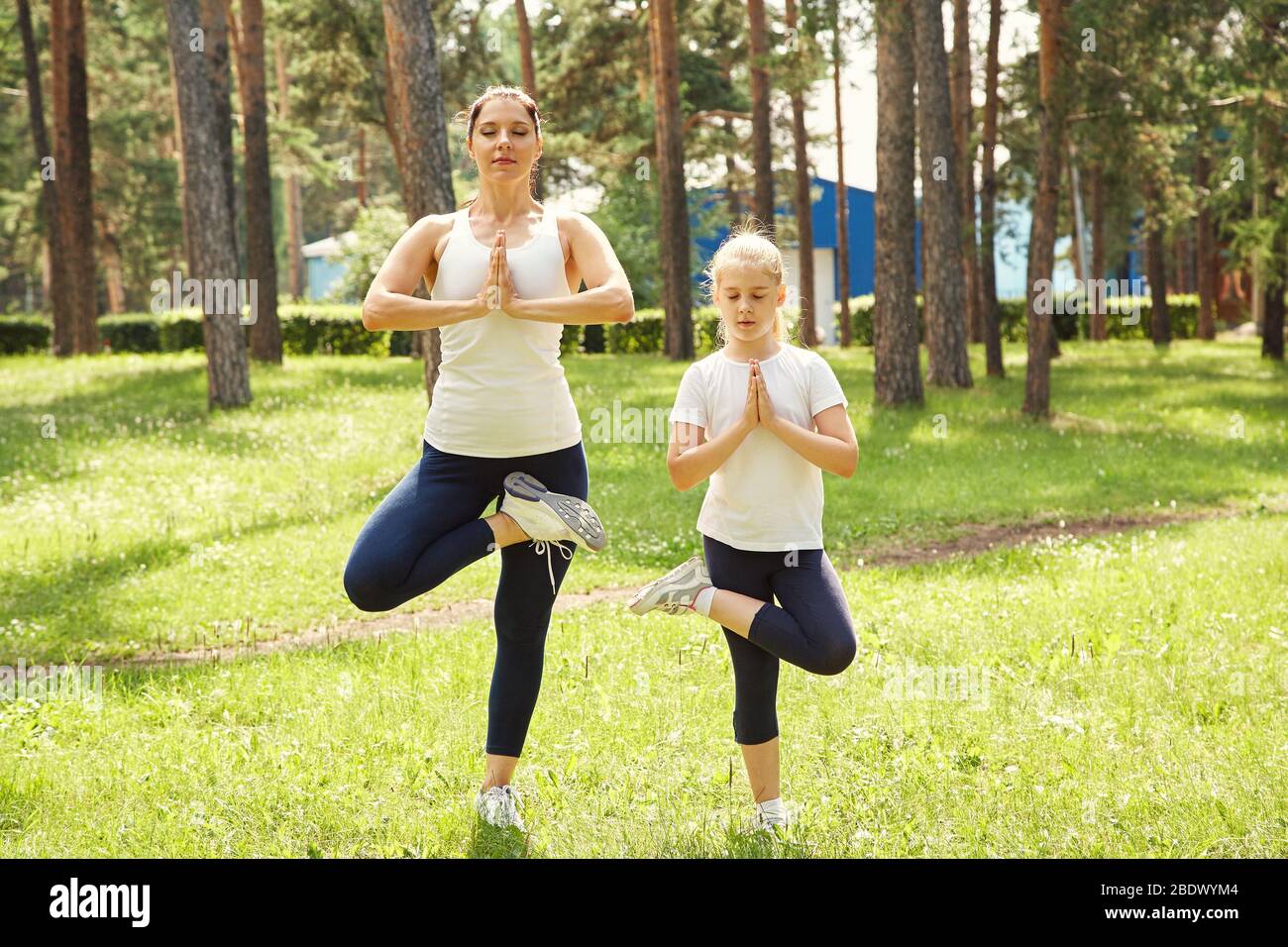 sporty mother and daughter. woman and child training in the park ...