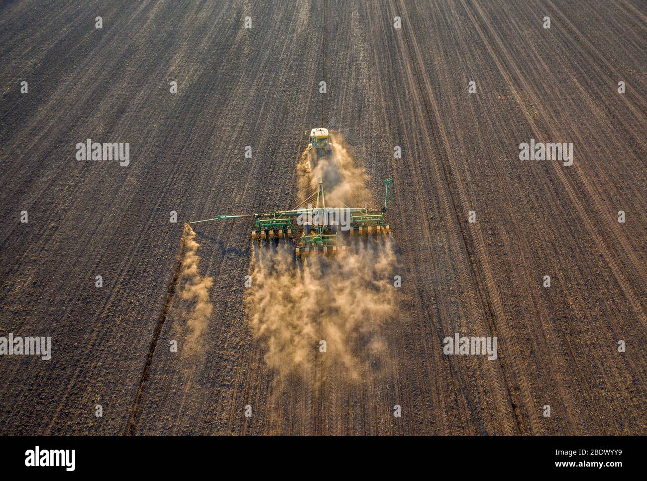 Spring field work, a tractor with a mounted seeder sow seeds in the ...