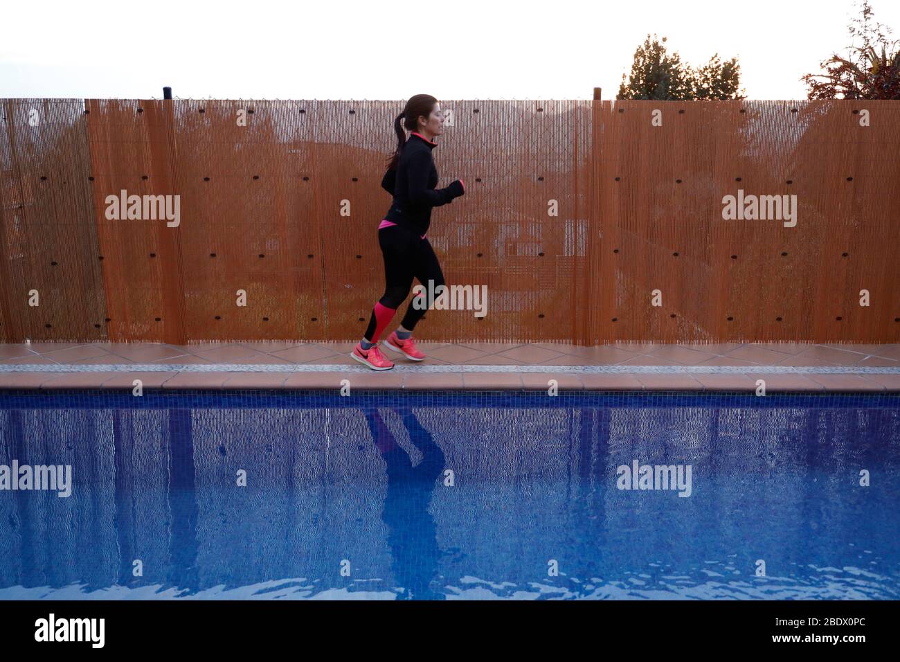 Woman running around pool perimeter at home during Covid19 confinement ...
