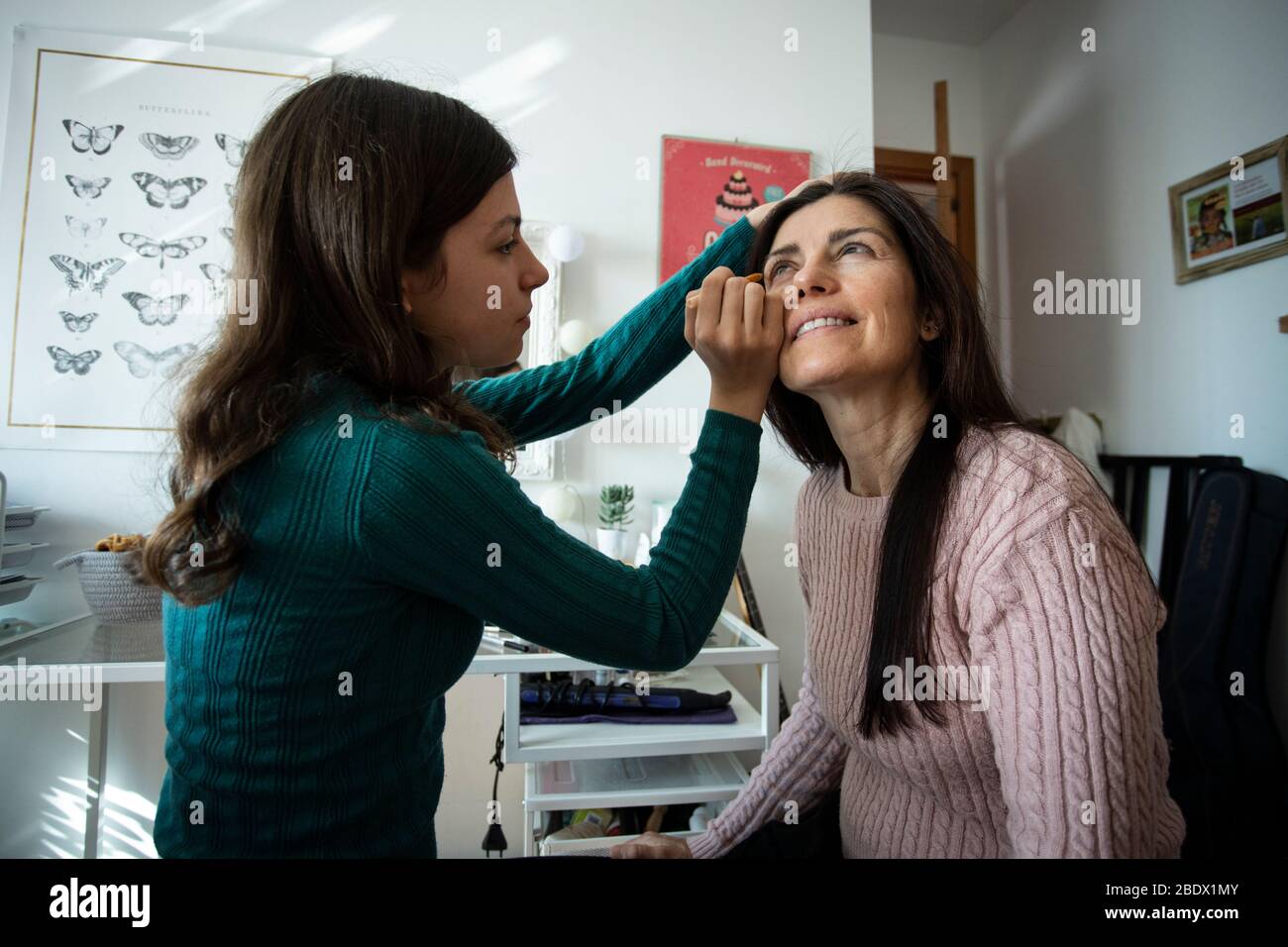Teenage girl putting make-up on her mother at home during Covid19 ...