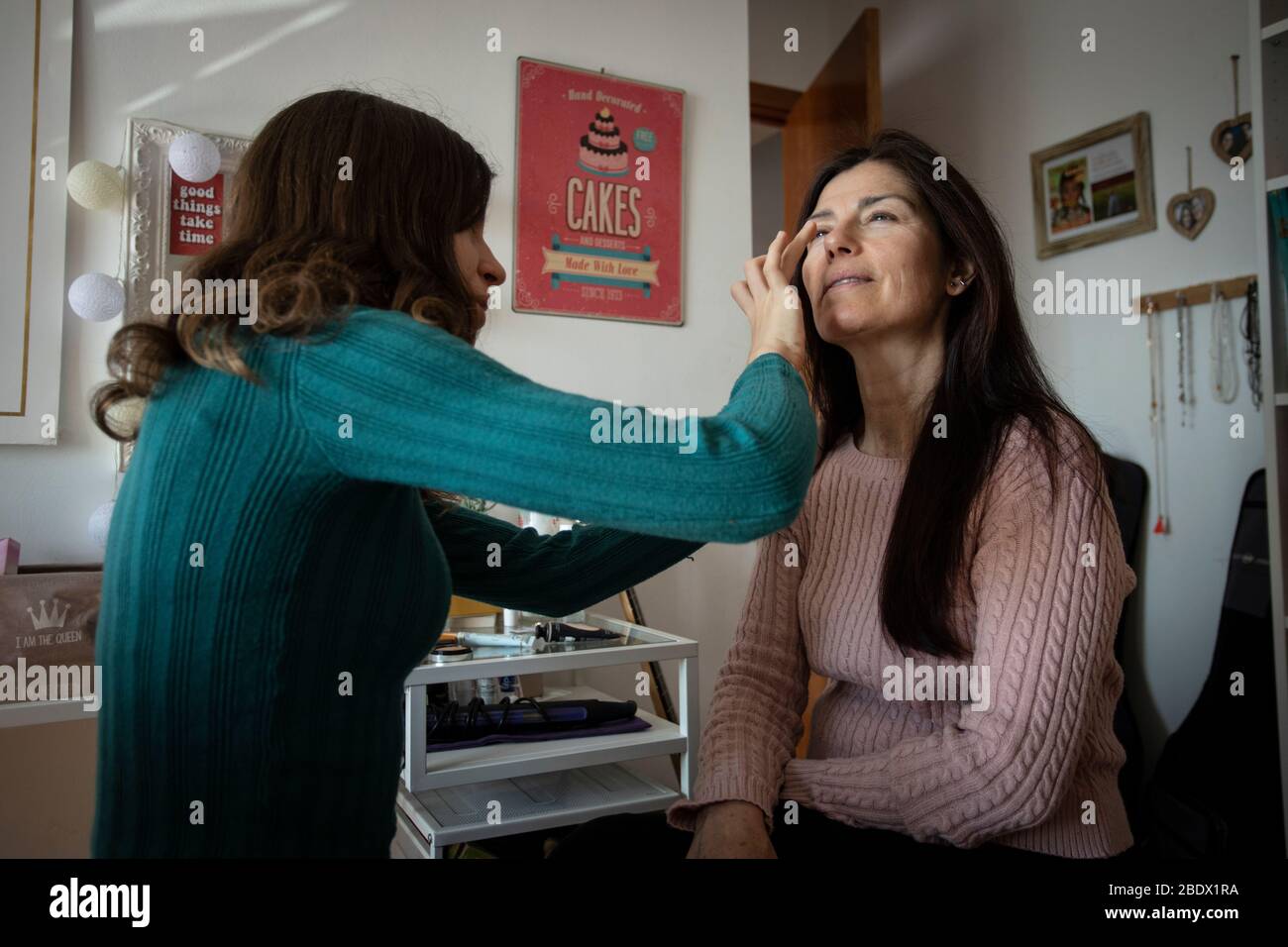 Teenage girl putting make-up on her mother at home during Covid19 ...
