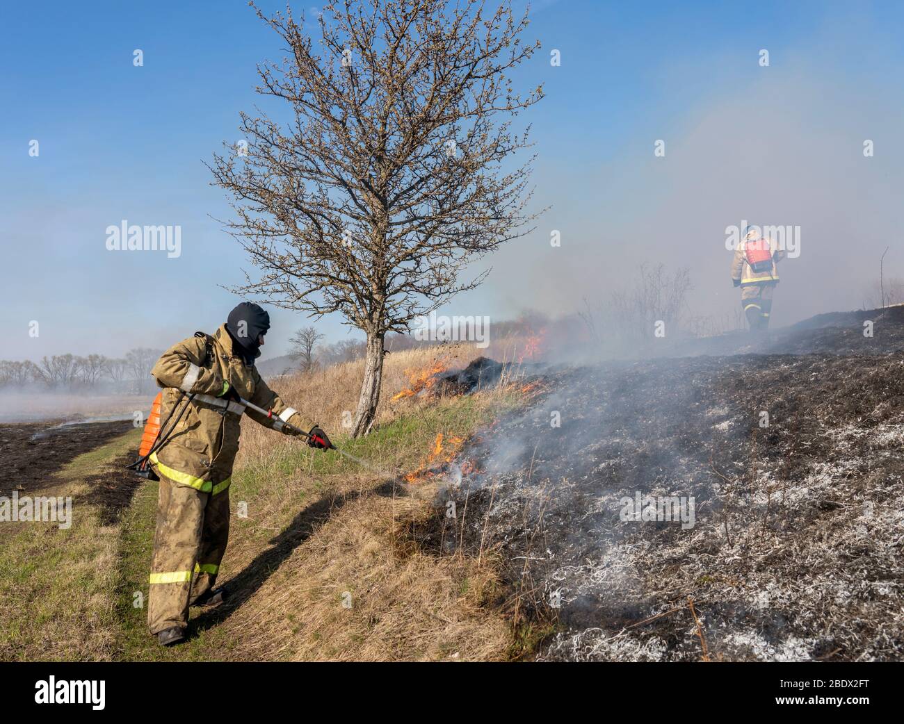 firefighters extinguish the flames of burning grass Stock Photo - Alamy