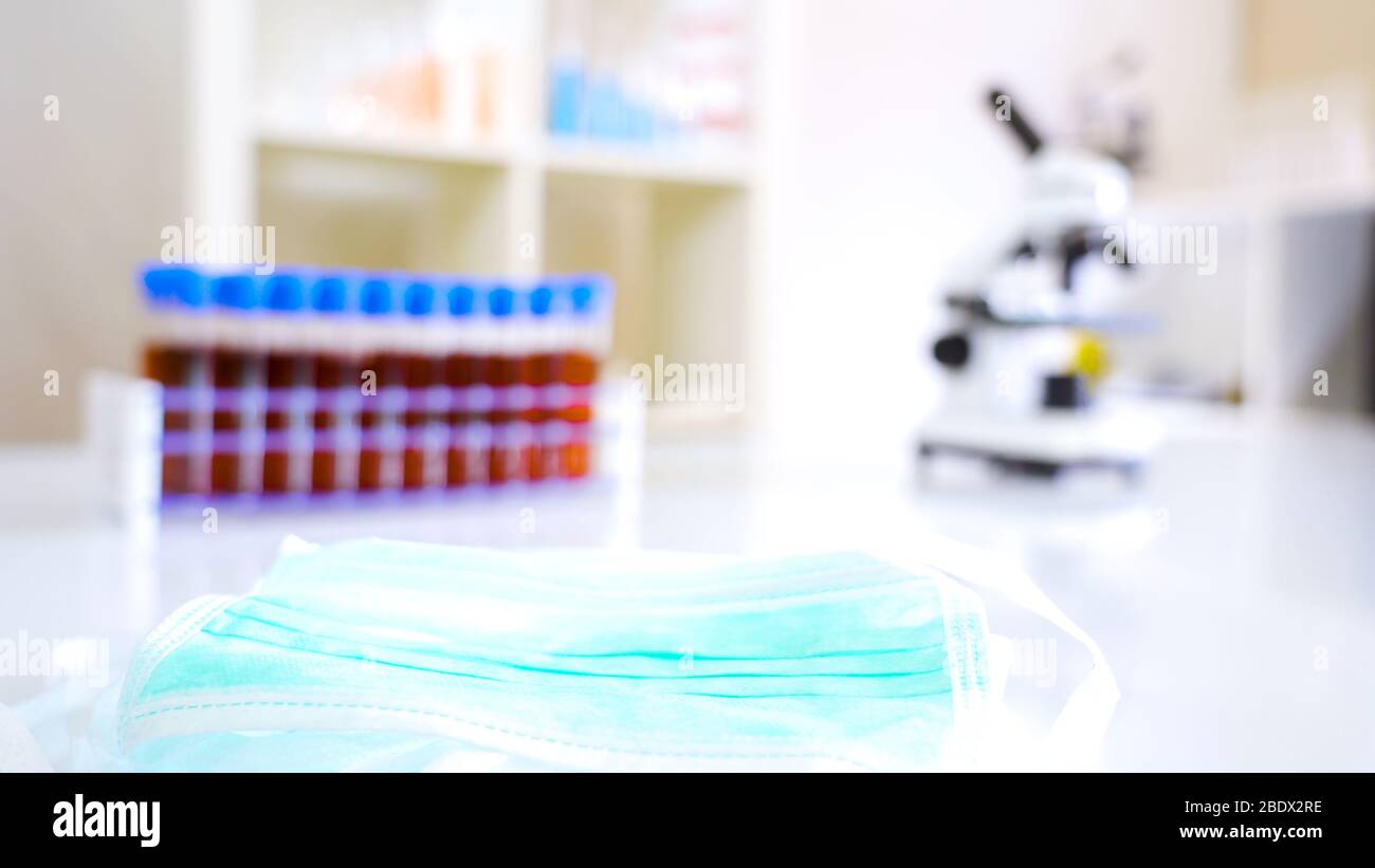 The face mask and the test tubes on the table and the microscope inside ...