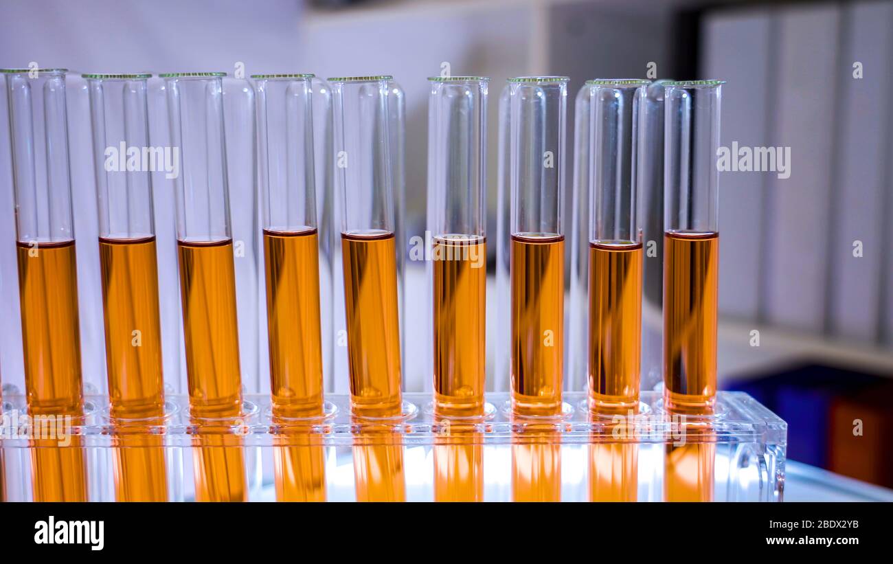 The orange chemicals inside the test tubes on the rack in the ...