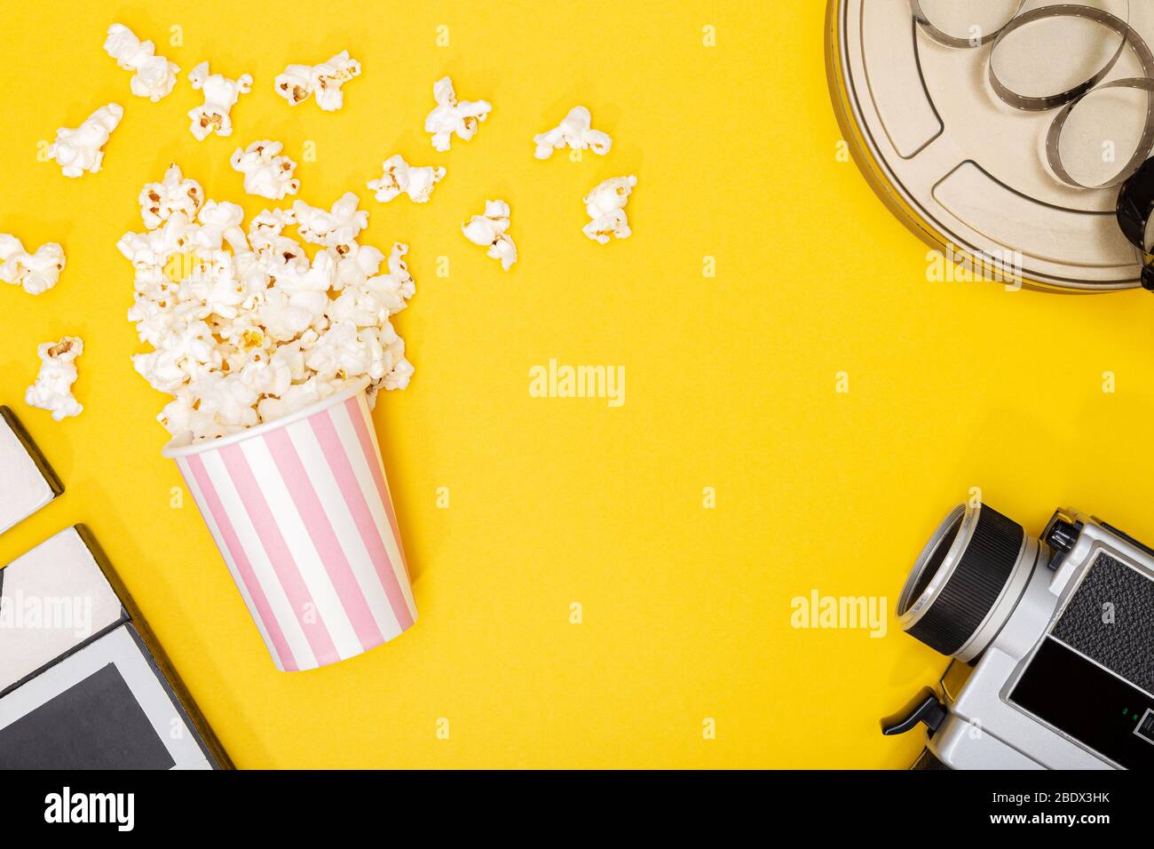 Popcorn bucket, film camera, can and clapper on yellow background ...