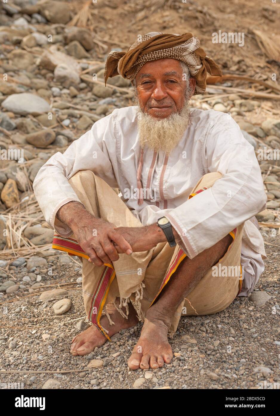 An Omani farmer, wearing a muzzar (traditional woollen turban), relaxes ...