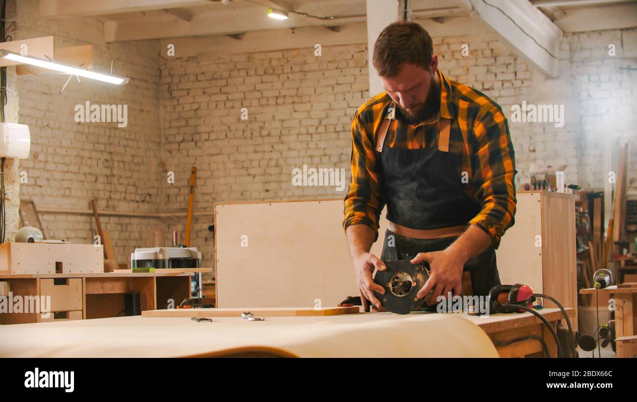 Carpentry industry - man worker sets up the grinding machine on the ...