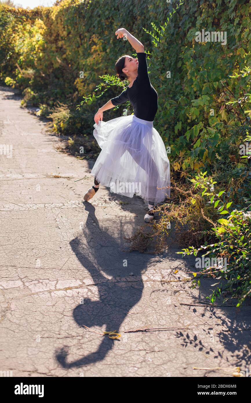 Woman ballerina in a white ballet skirt dancing in pointe shoes in ...