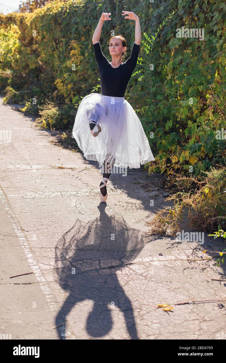 Woman ballerina in a white ballet skirt dancing in pointe shoes in ...