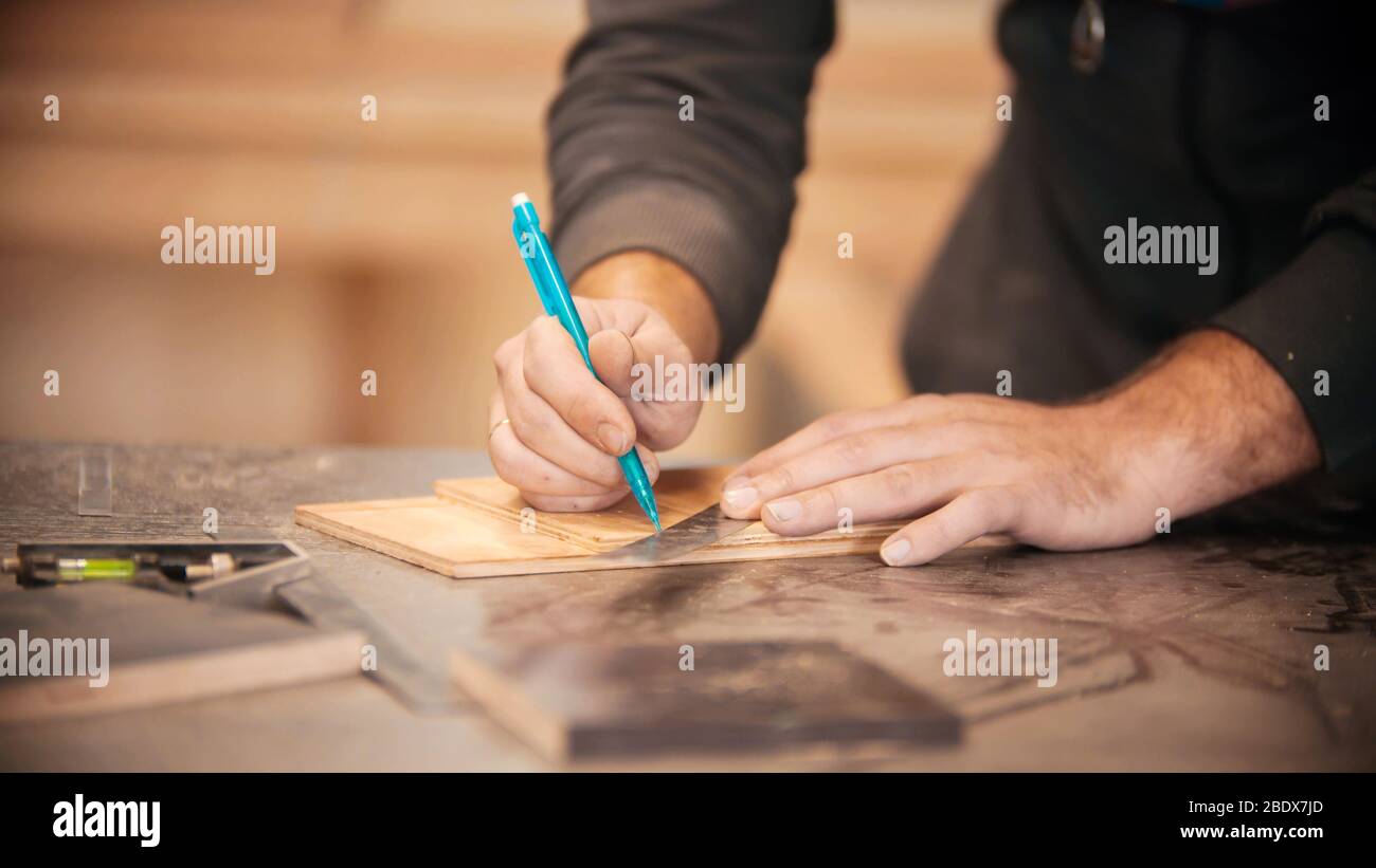 Carpentry working - making marks on the wood with a pencil. Mid shot ...