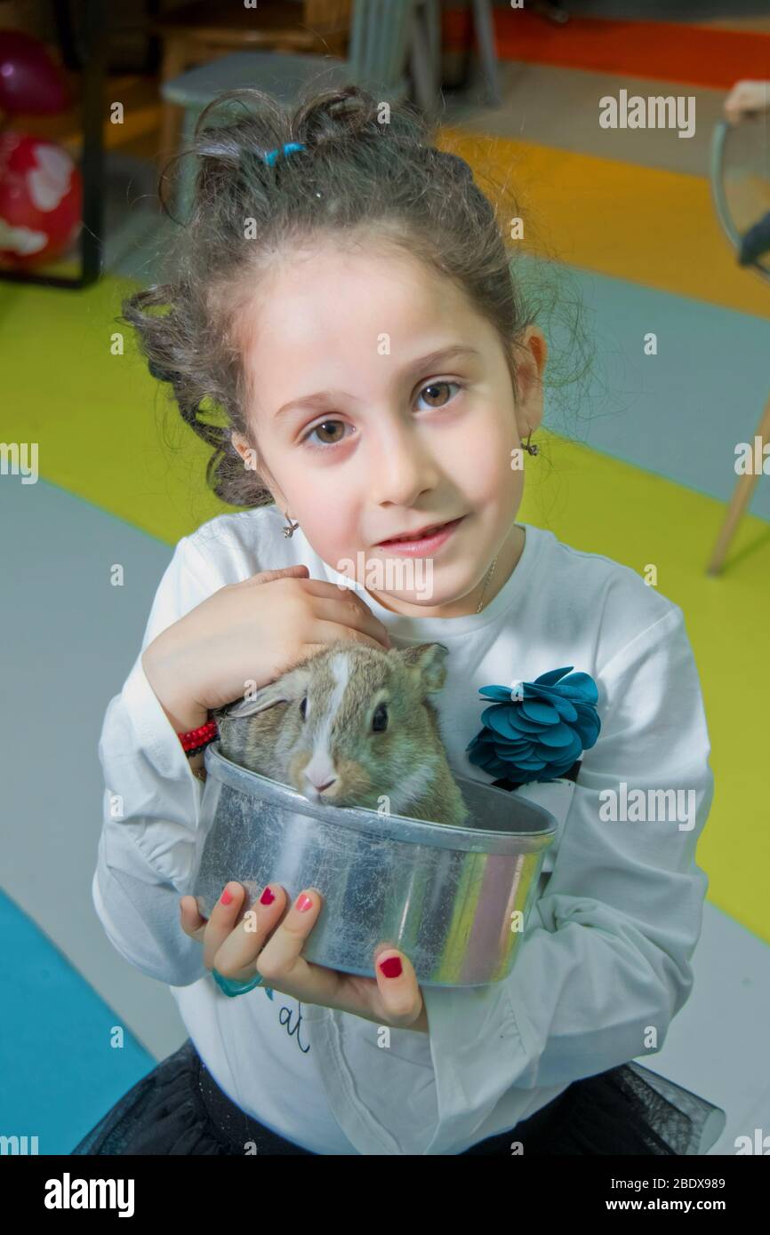 The child is holding a rabbit . Happy young girl holding rabbit ...