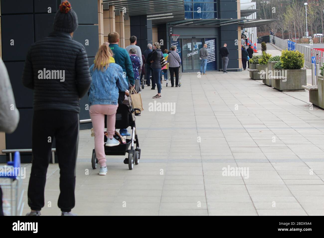 Long queue of shoppers standing at a safe distance from each other ...