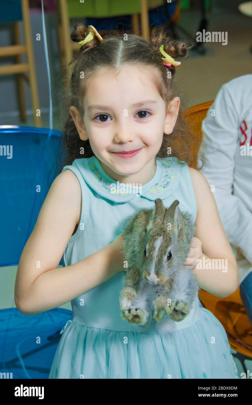 The child is holding a rabbit . Happy young girl holding rabbit ...