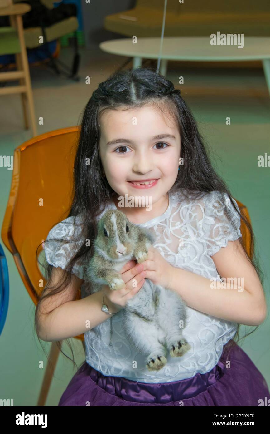The child is holding a rabbit . Happy young girl holding rabbit ...